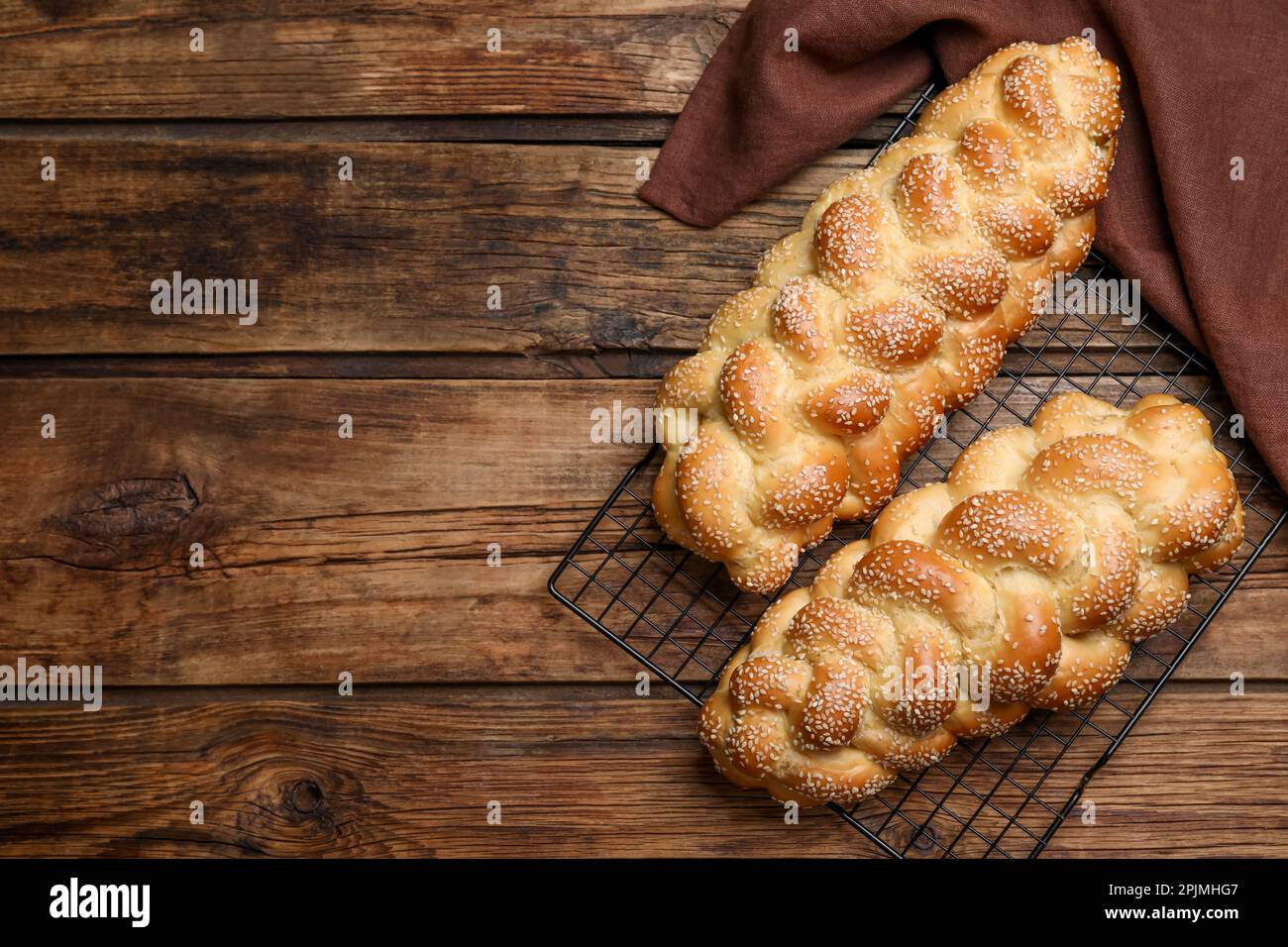 Homemade braided breads and cooling rack on wooden table, top view with ...