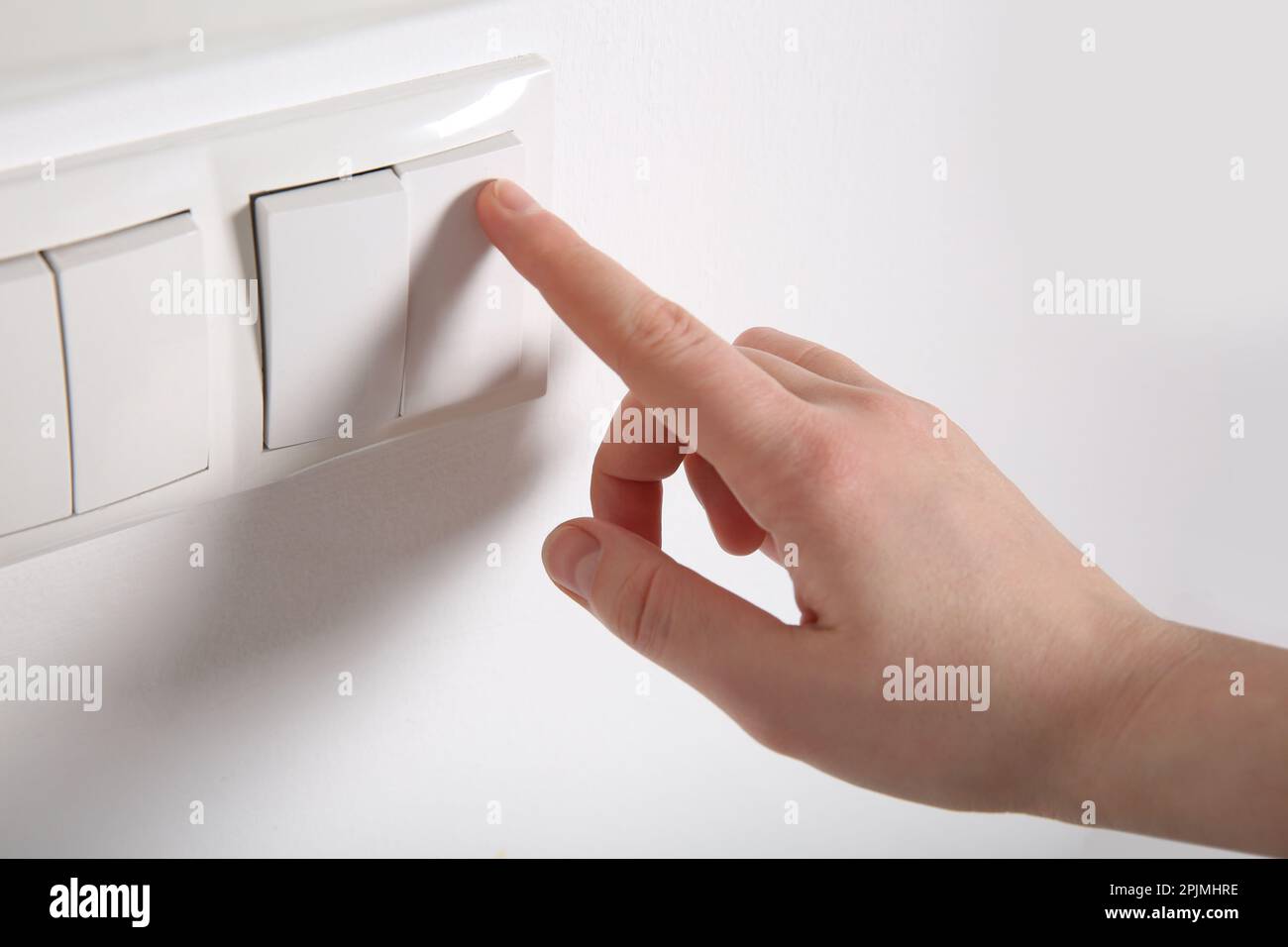 Woman turning off light switch indoors, closeup. Energy saving concept ...