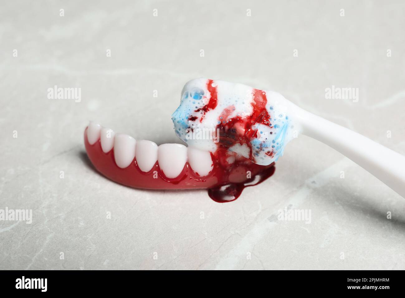 Gum model and toothbrush with blood on light grey table, closeup Stock ...