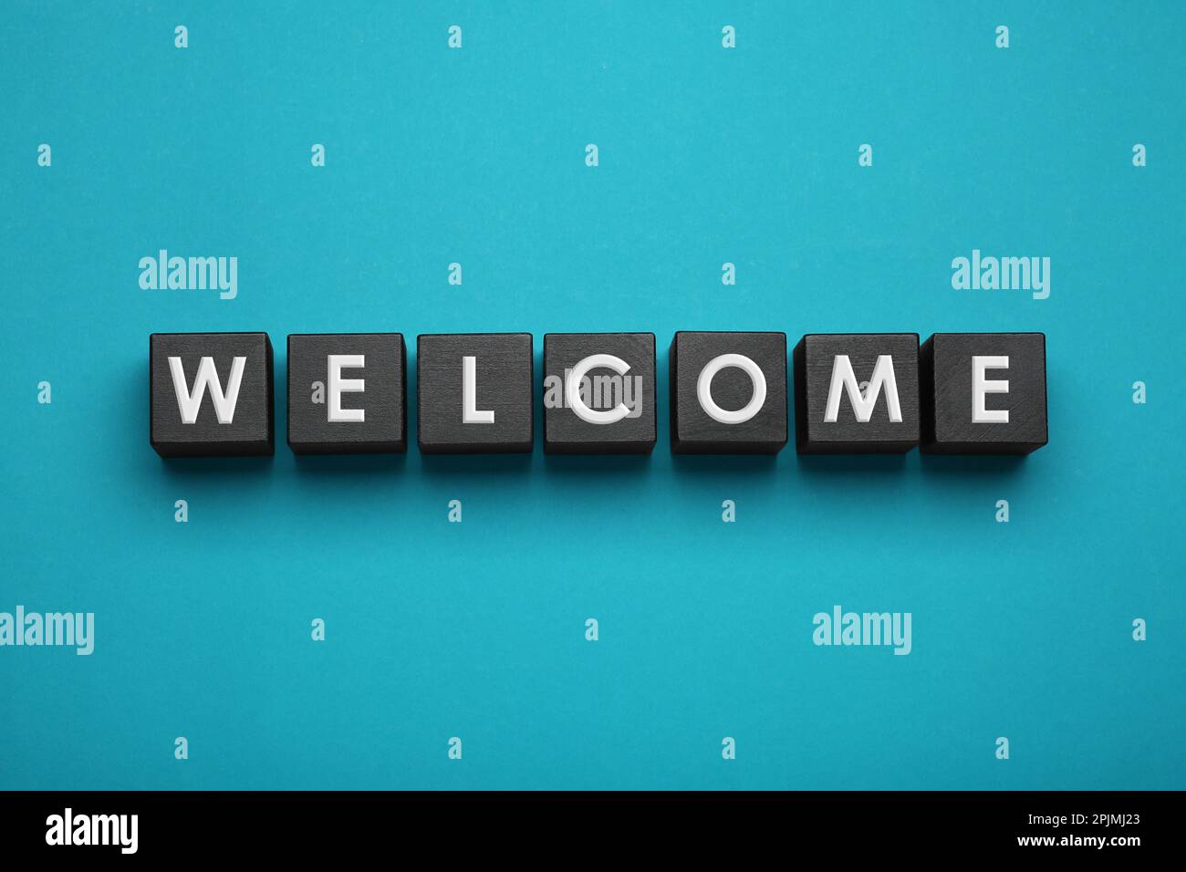 Word Welcome made of black cubes with letters on turquoise background ...