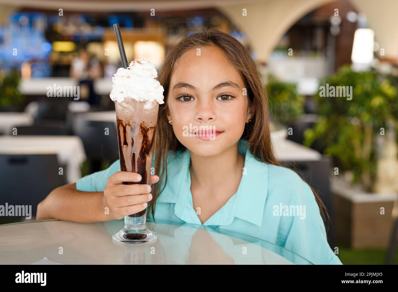Beautiful child kid girl eating a chocolate shake in a restaurant. Cold ...
