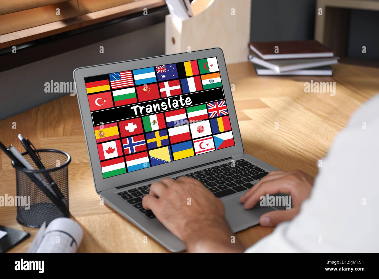Translator using modern laptop with images of different flags on screen ...