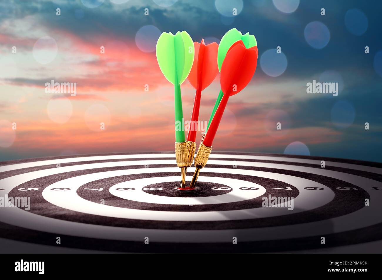 Darts hitting target on board against blurred of view sky at sunset ...