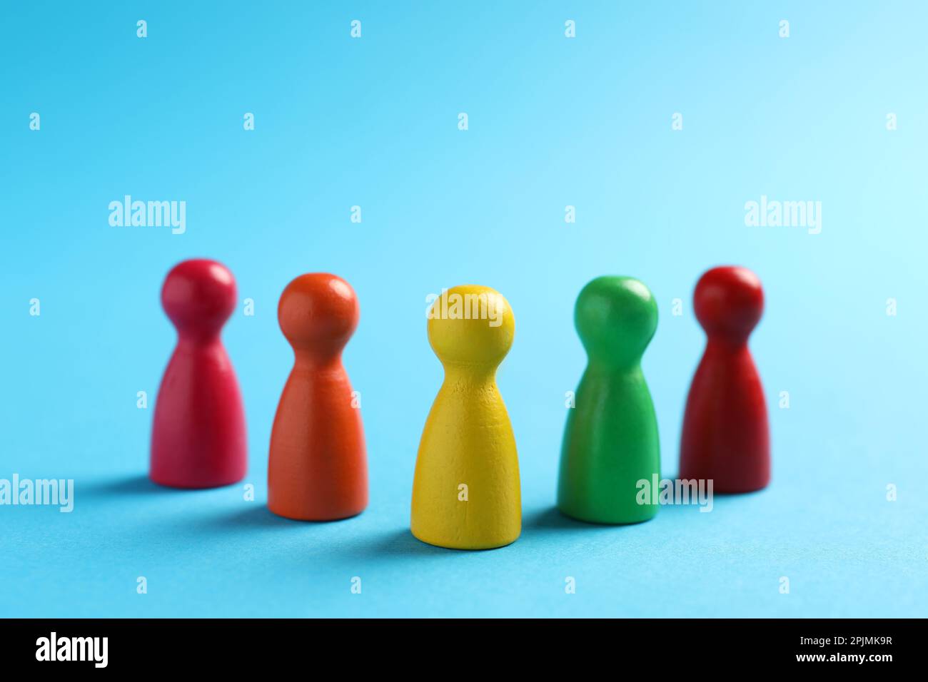 Colorful pawns on light blue background, closeup. Social inclusion ...