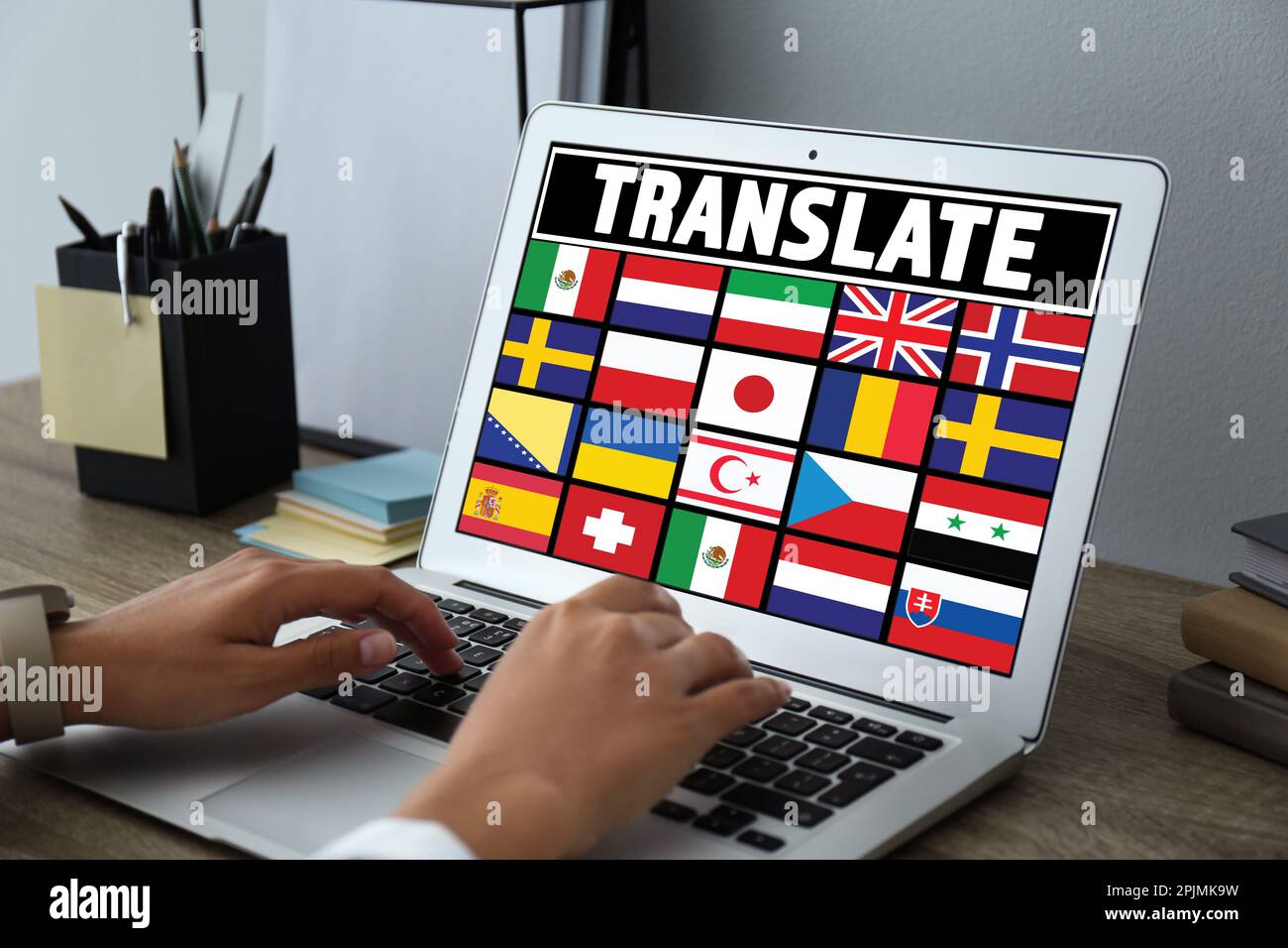 Translator using modern laptop with images of different flags on screen ...