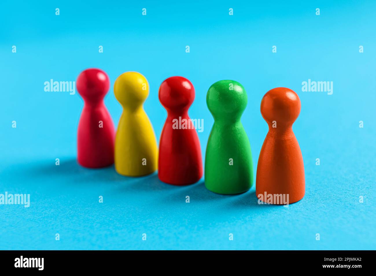 Colorful pawns on light blue background, closeup. Social inclusion ...