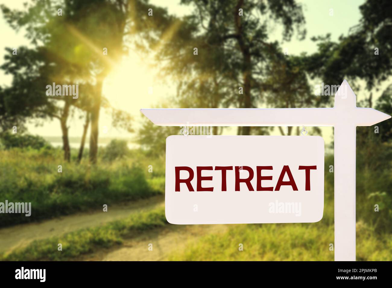 Wooden sign with word Retreat and beautiful view of sunset in conifer ...