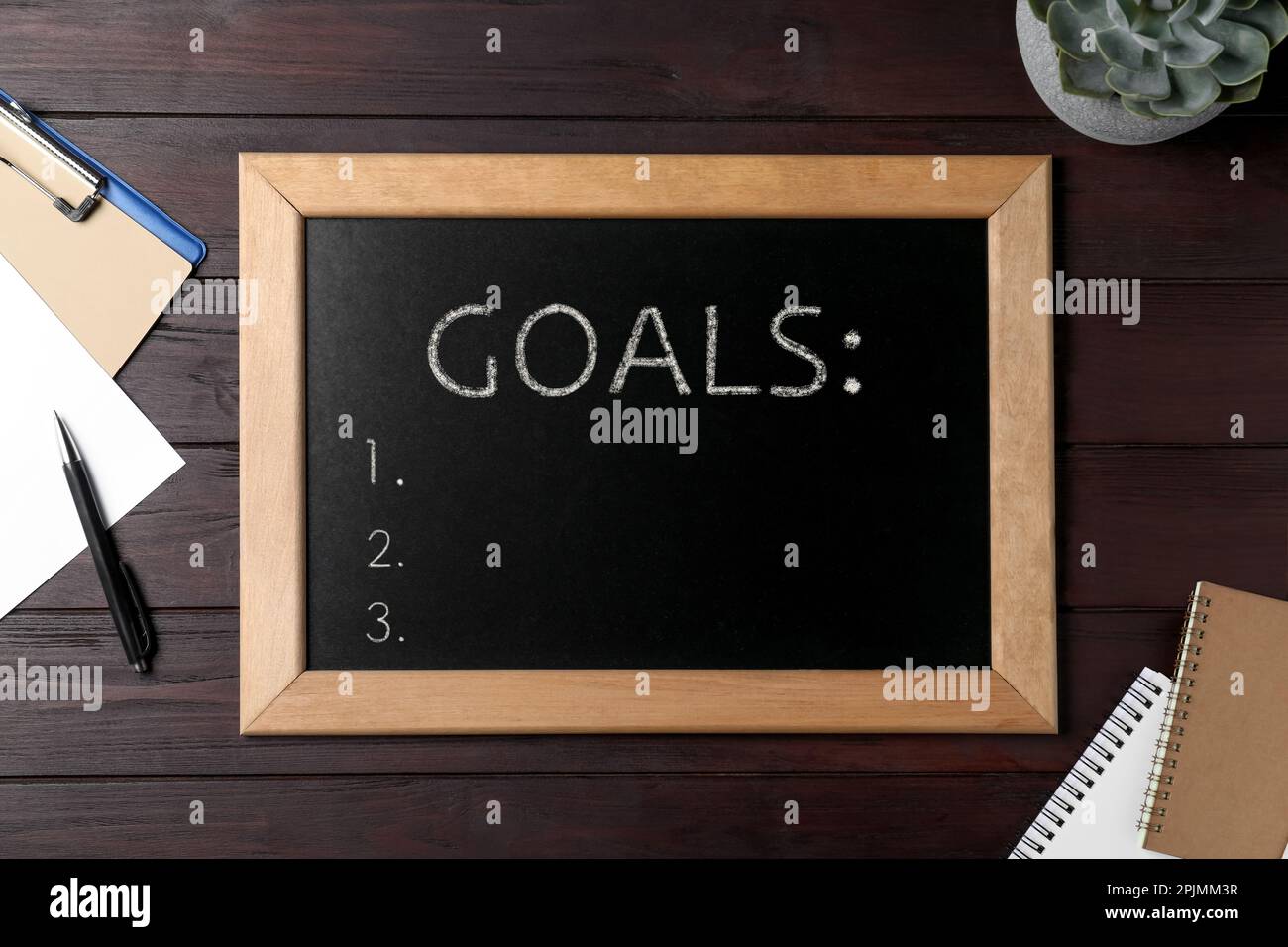 Blackboard with word GOALS and empty checklist on wooden background ...