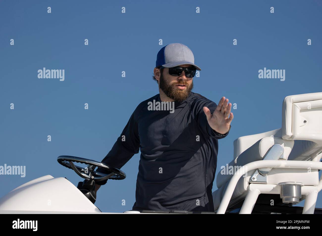 Man gesturing from the helm of a boat Stock Photo - Alamy