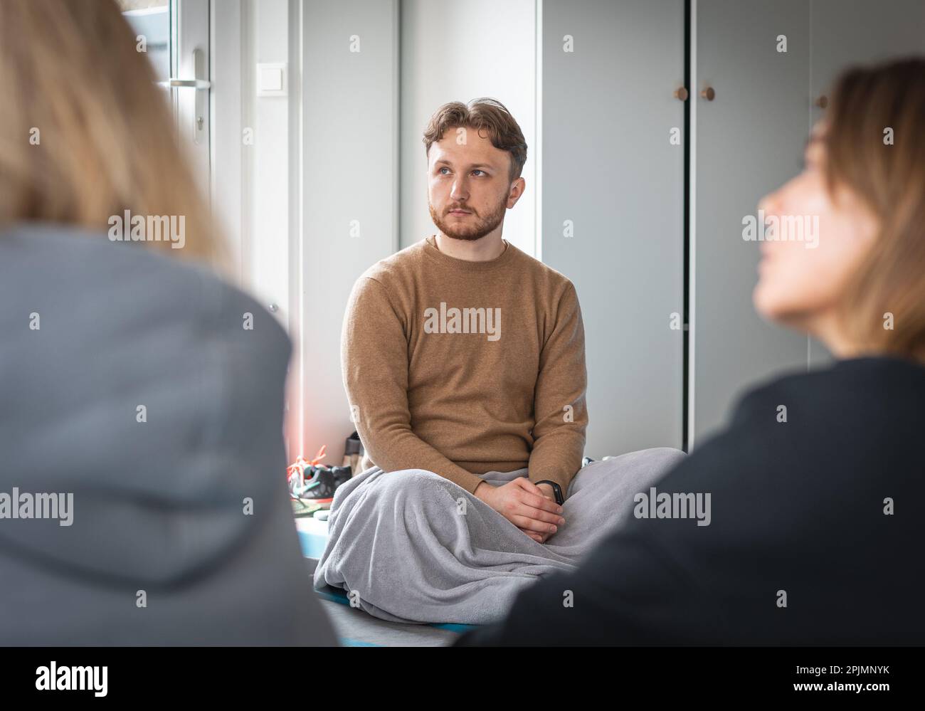 Boy sitting on a mat with a blanket during a yoga class or group ...
