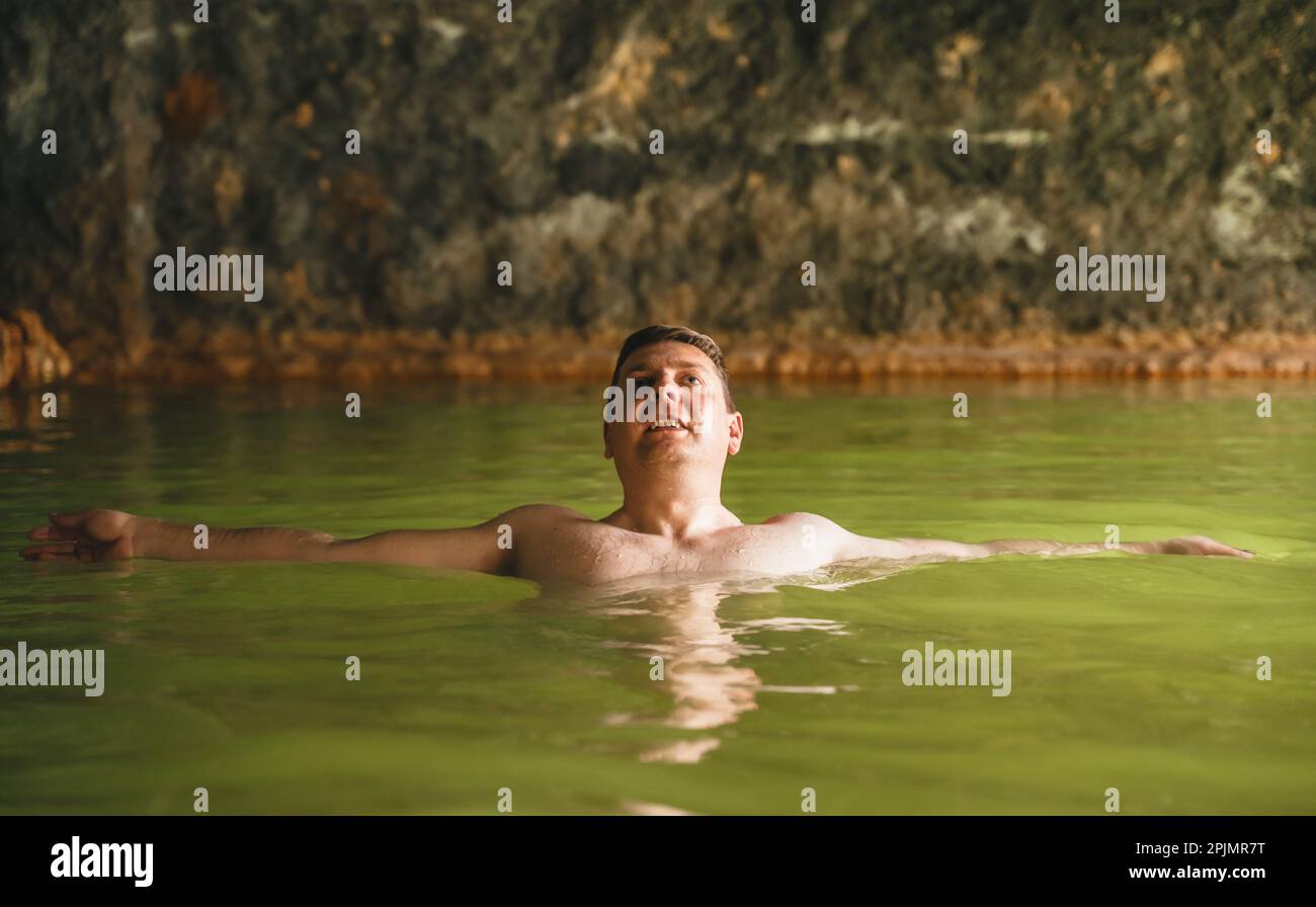 Man bathe swim in outdoor cave, dirty hot springs. Thermal water bath ...