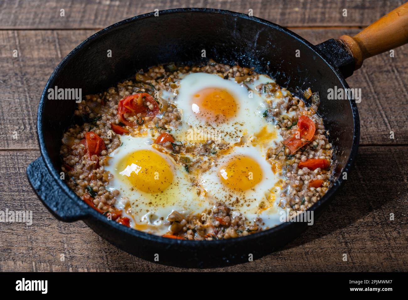 Boiled buckwheat with fried eggs, red peppers, tomato and onions, close ...