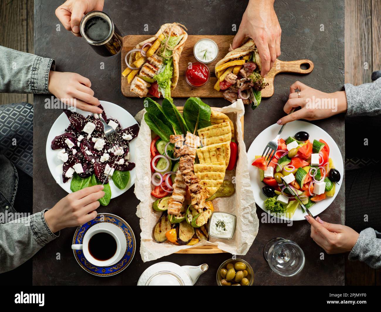 People eating Greek food. Greek cuisine assortment on dark tabletop ...
