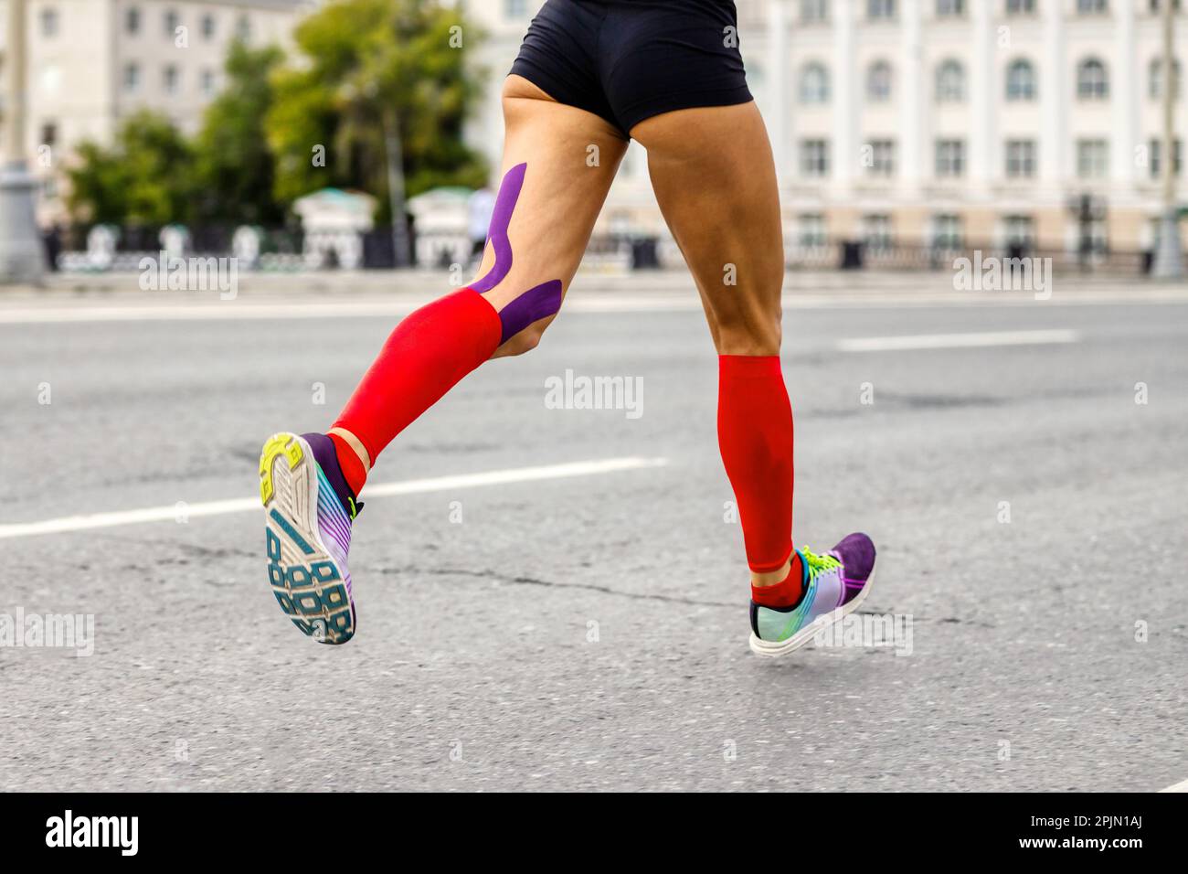 legs female runner in compression socks and kinesio tape on knee to running marathon, woman ...
