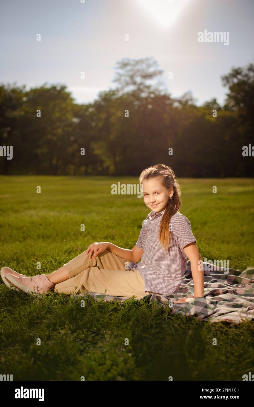 happy child girl in casual clothes chilling in green park, sitting on ...