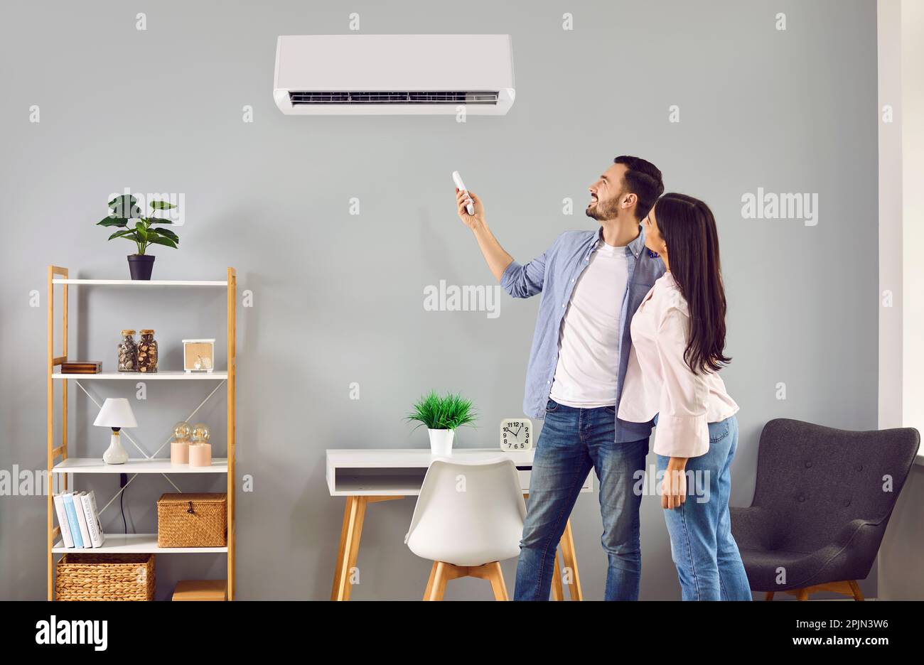 Young family couple setting up the temperature on a modern air conditioner at home Stock Photo ...