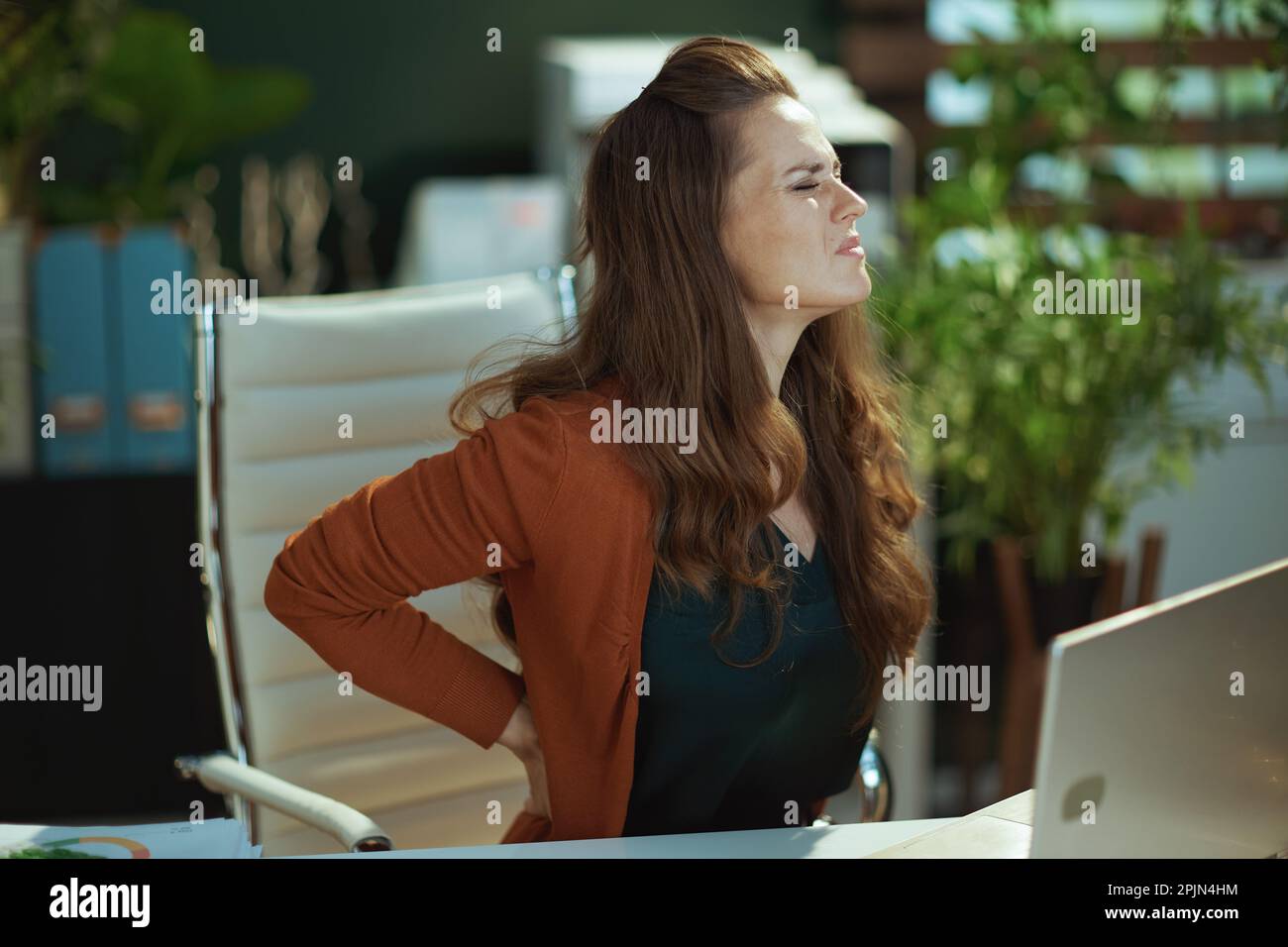 sad modern small business owner woman with back pain in the modern ...