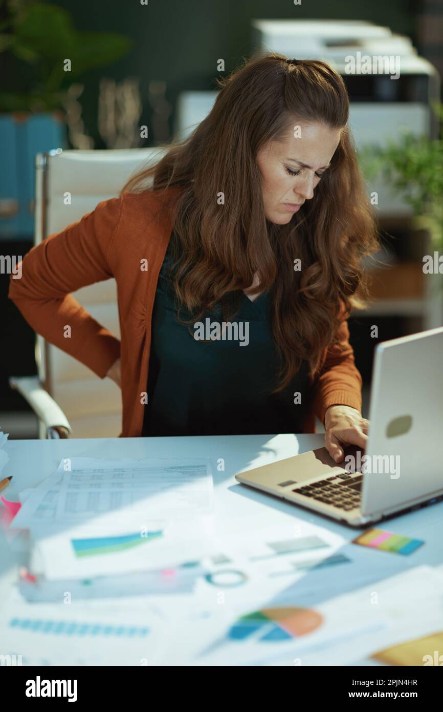 stressed modern small business owner woman with laptop and back pain in ...