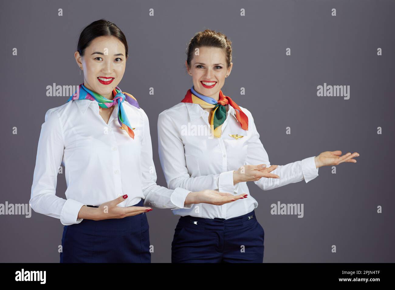 smiling elegant female stewardesses in blue skirt, white shirt and ...