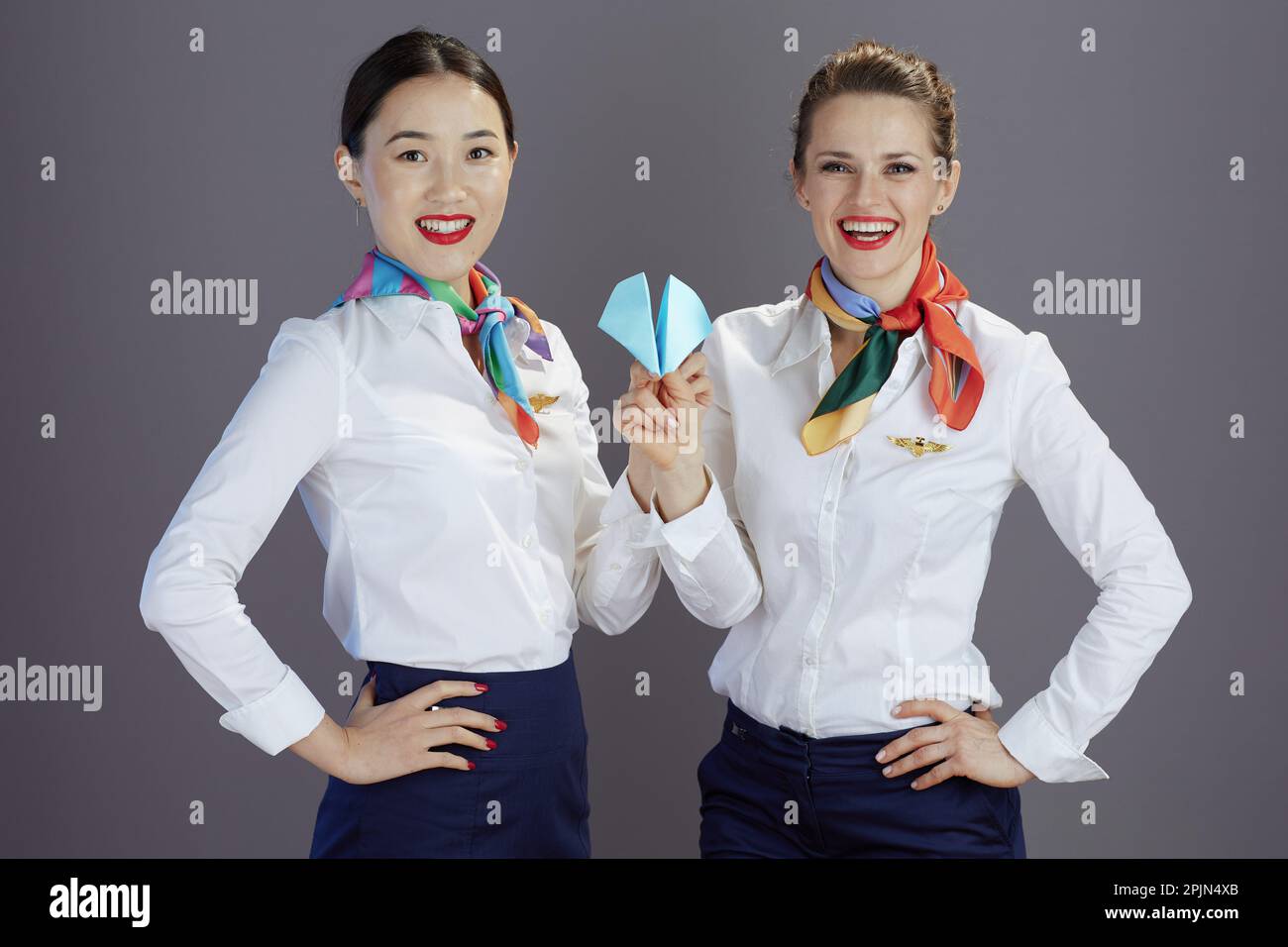 smiling modern flight attendant women in blue skirt, white shirt and ...