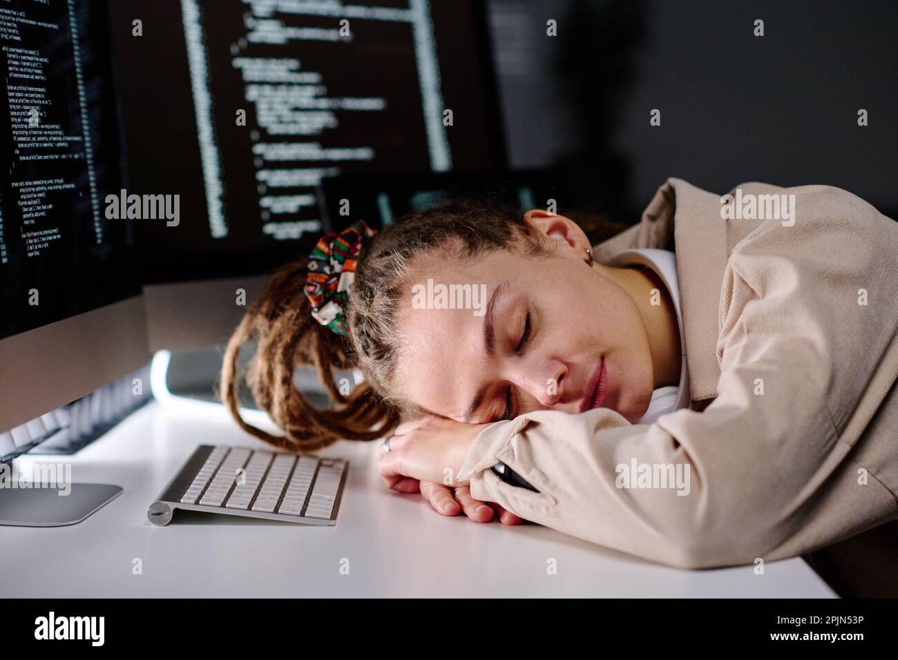 Young exhausted female IT engineer sleeping with her head on desk by ...