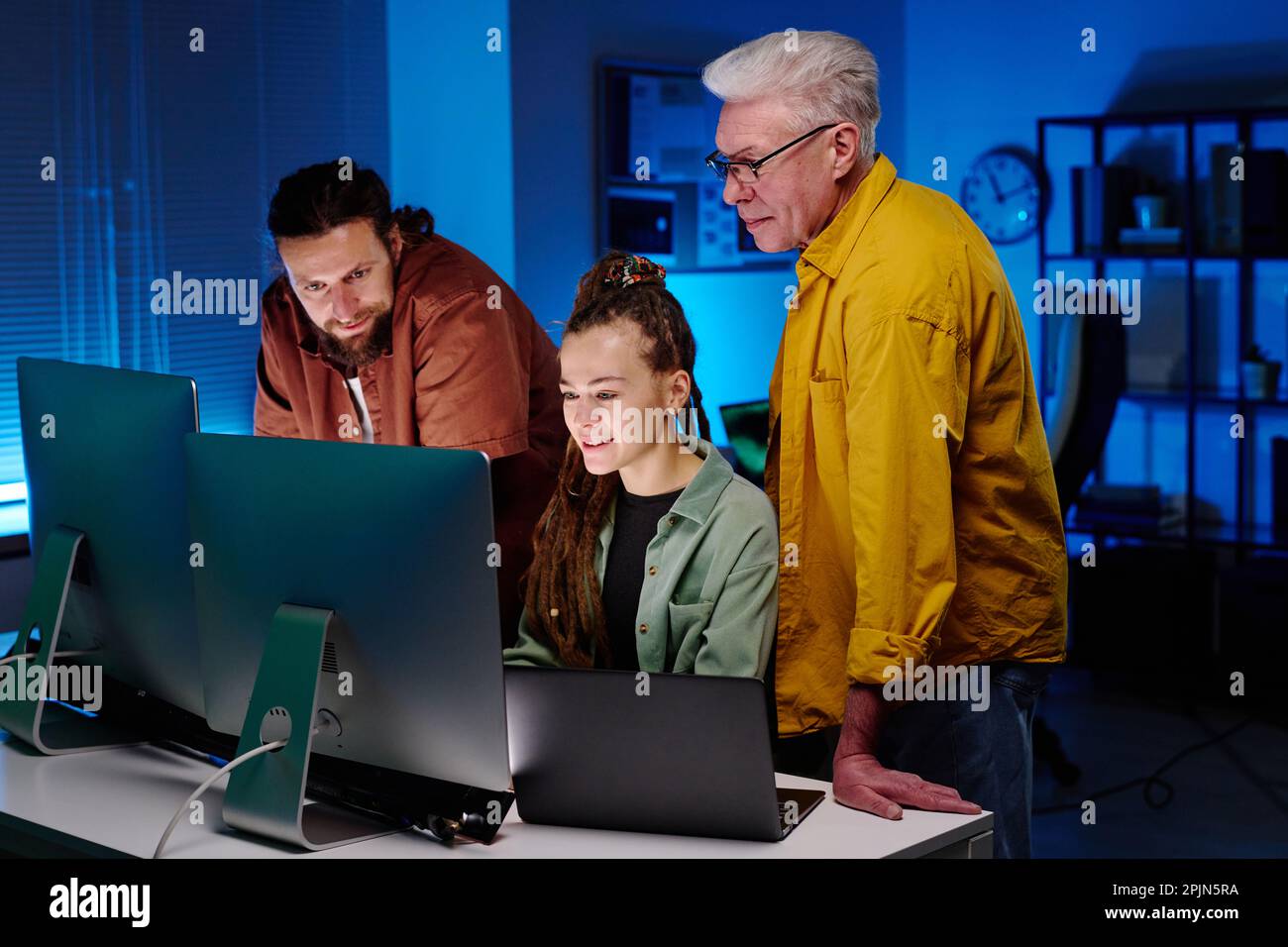 Group of IT engineers looking at screen of desktop computer at working ...