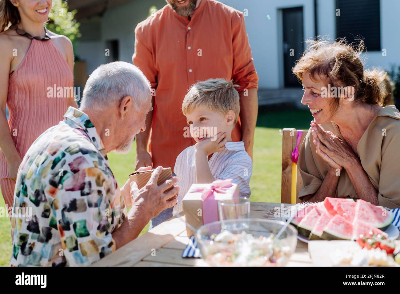 Happy little boy giving birthday present to his senior grandfather at ...