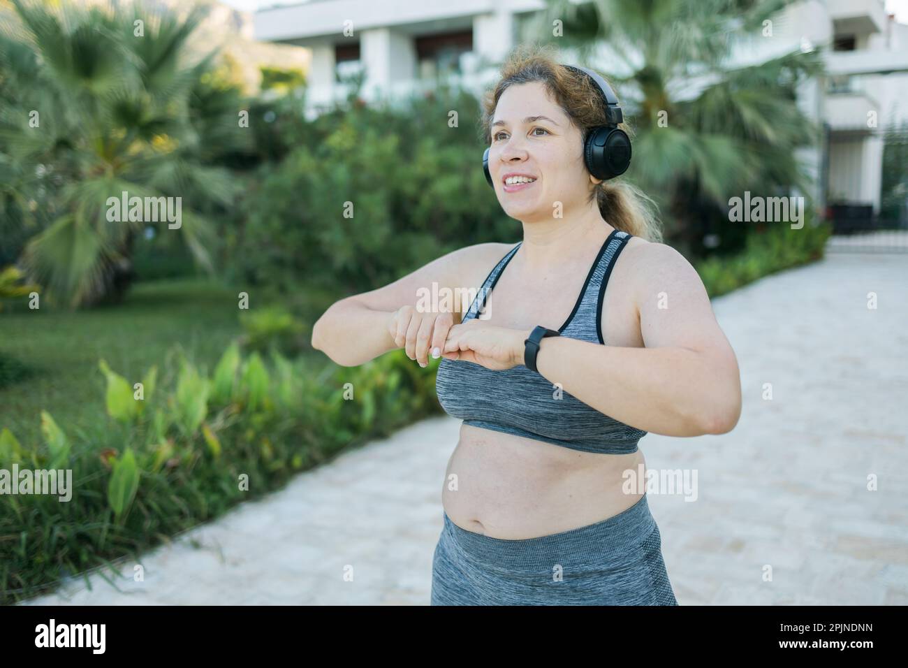Adorable fat woman in tracksuit is engaged in fitness outdoor side view ...