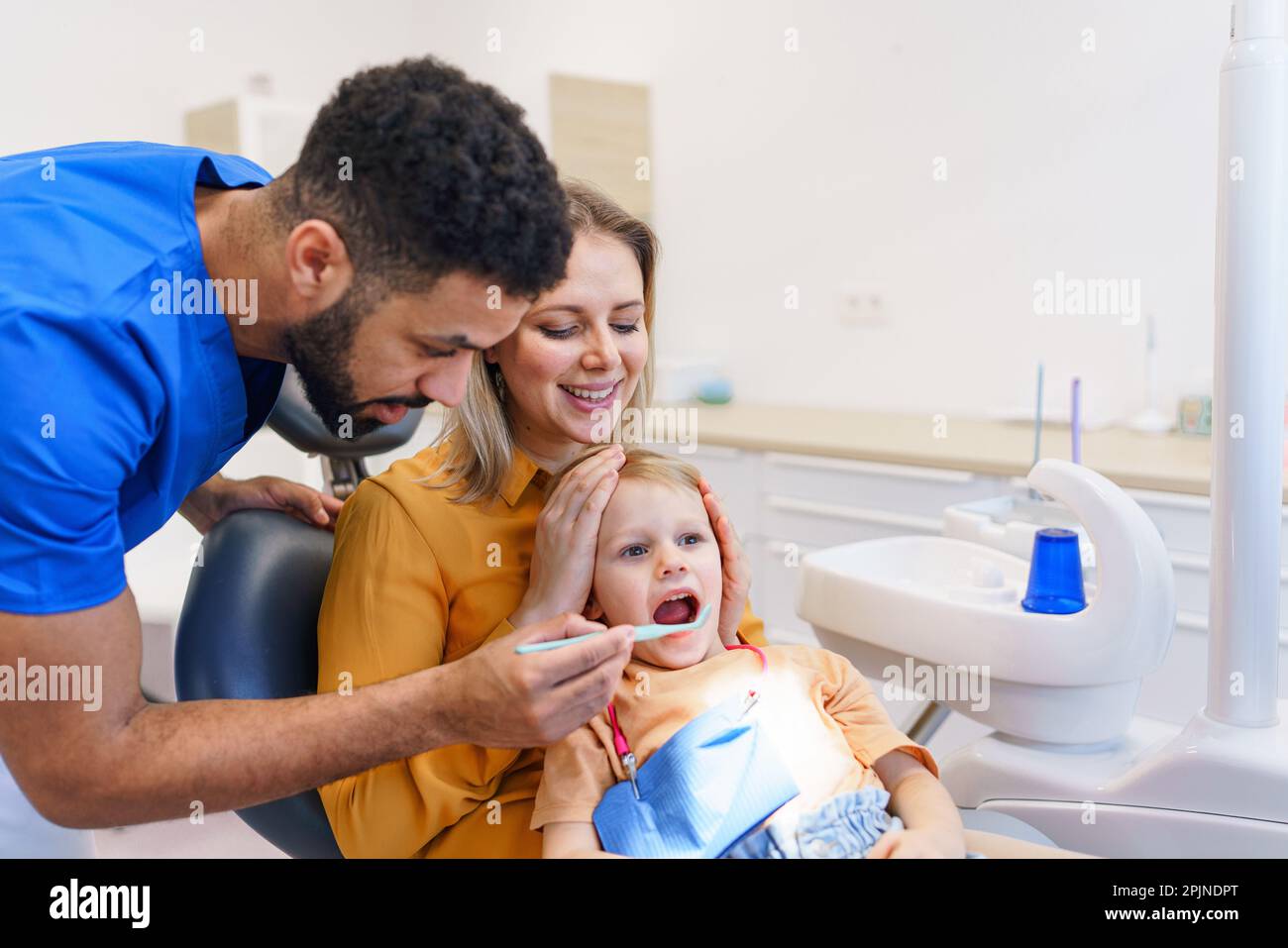 Little girl sitting with her mother on dentist chair, during preventive ...