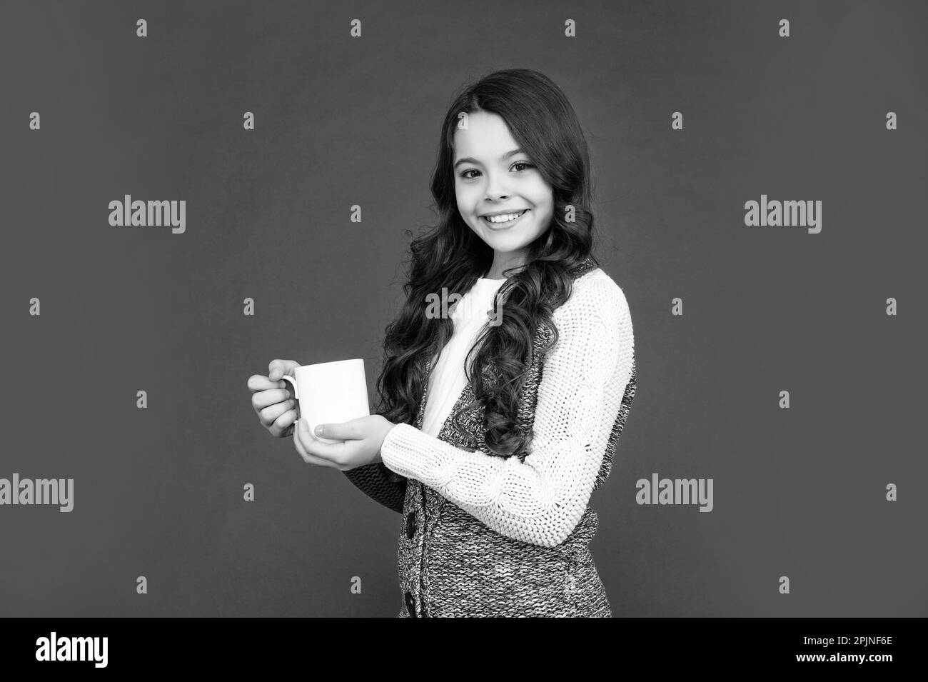 positive teen girl drink warm tea on red background. portrait of child ...