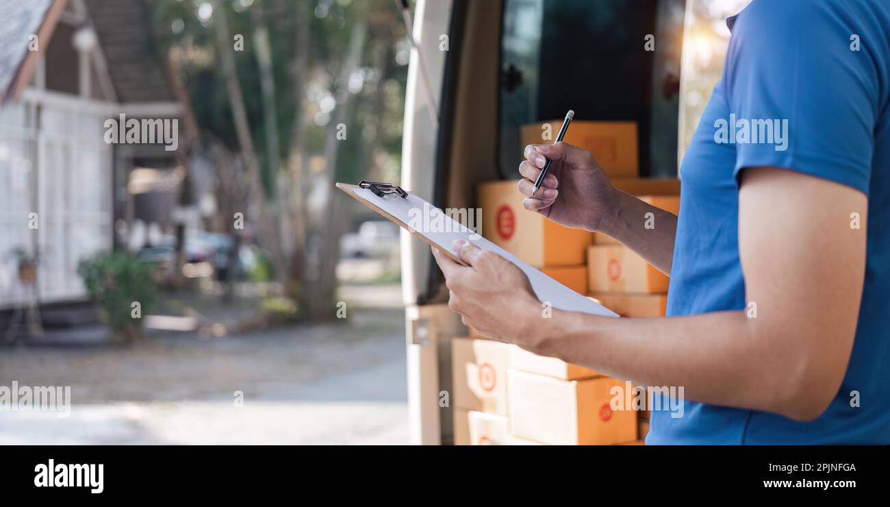 Delivery man signing checklist on clipboard. Male courier writing on ...