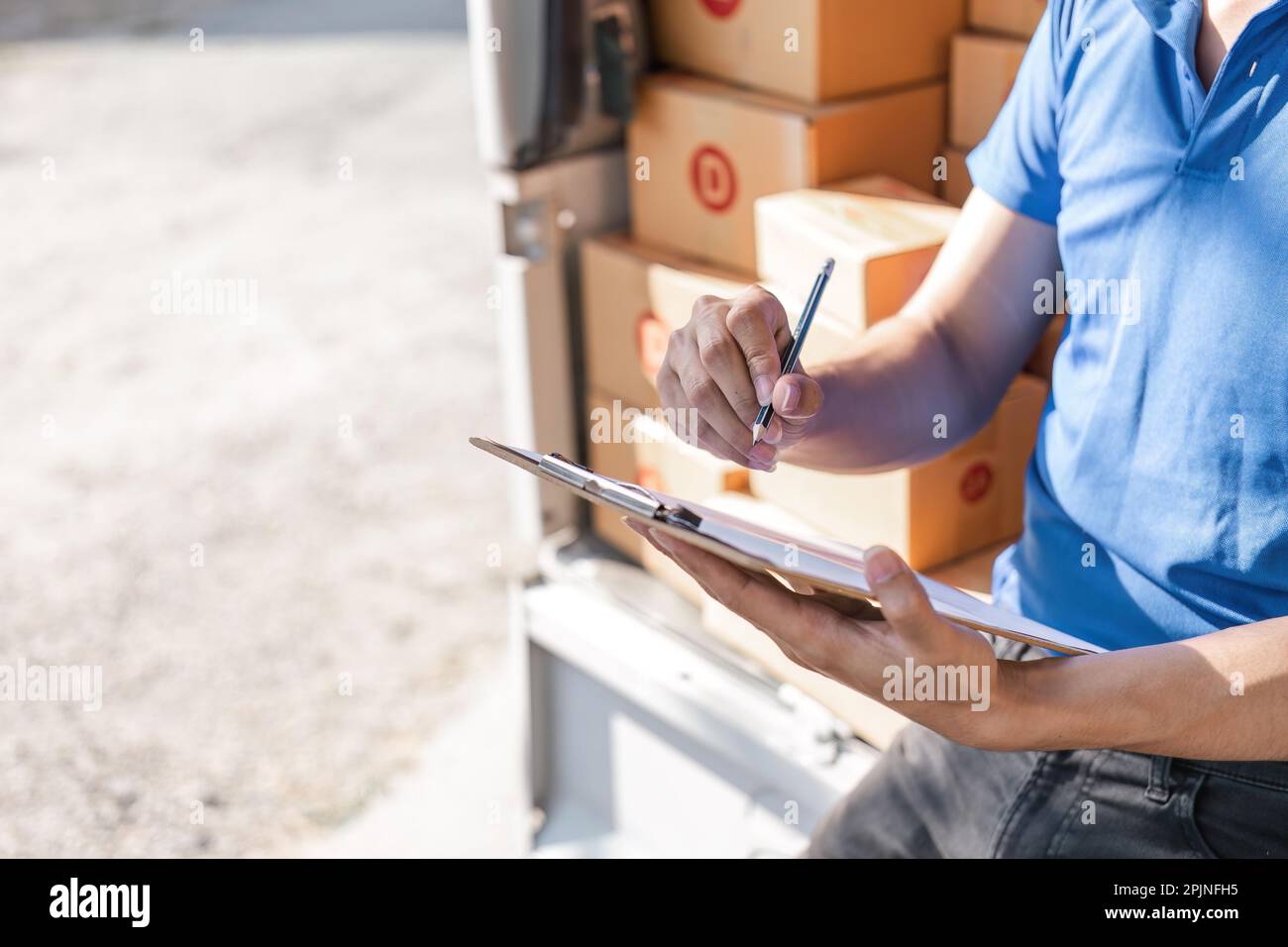 Delivery man signing checklist on clipboard. Male courier writing on ...