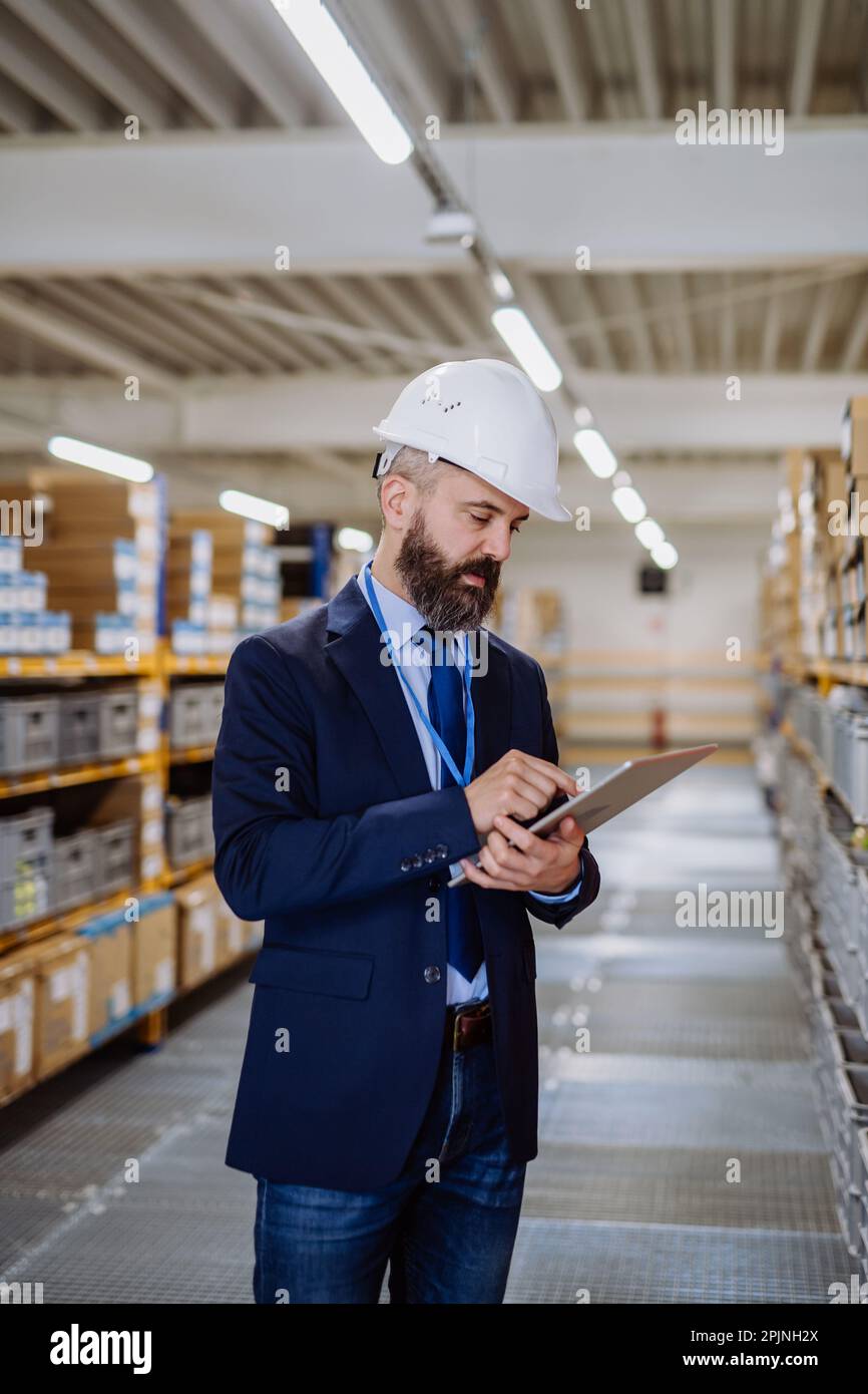 Manager in suit controlling goods in a waehouse Stock Photo - Alamy