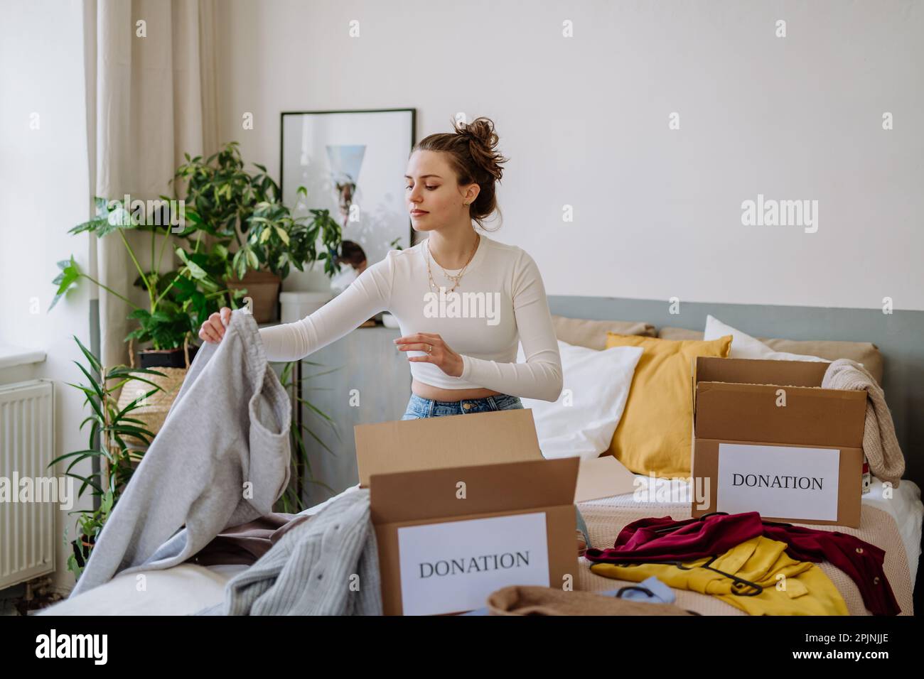Young woman giving her clothes to charity Stock Photo - Alamy