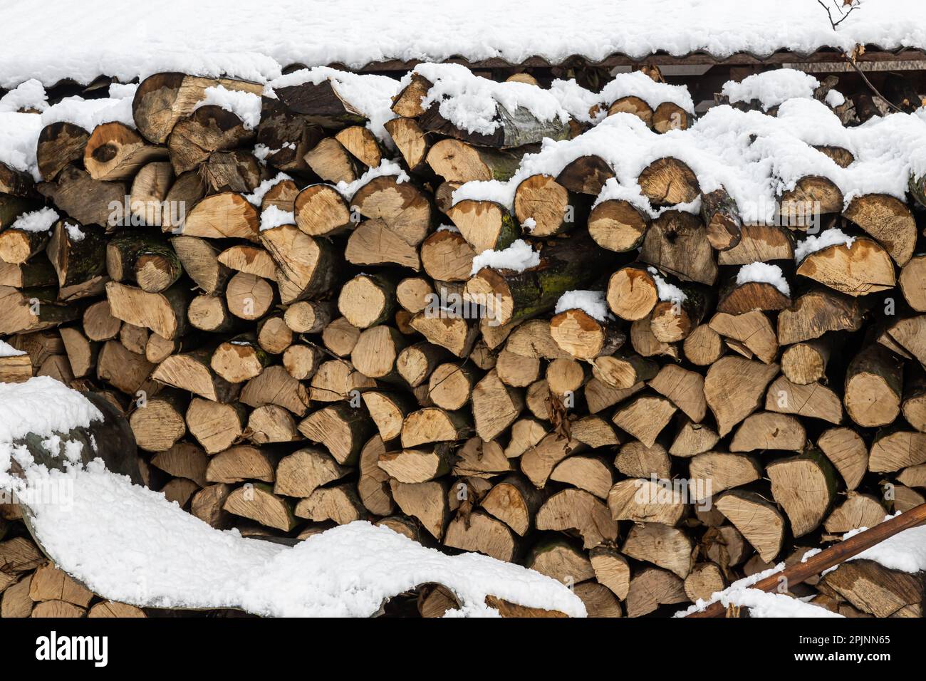 Snow covered firewood. Stack of wood cut. Snow on the timber stack ...