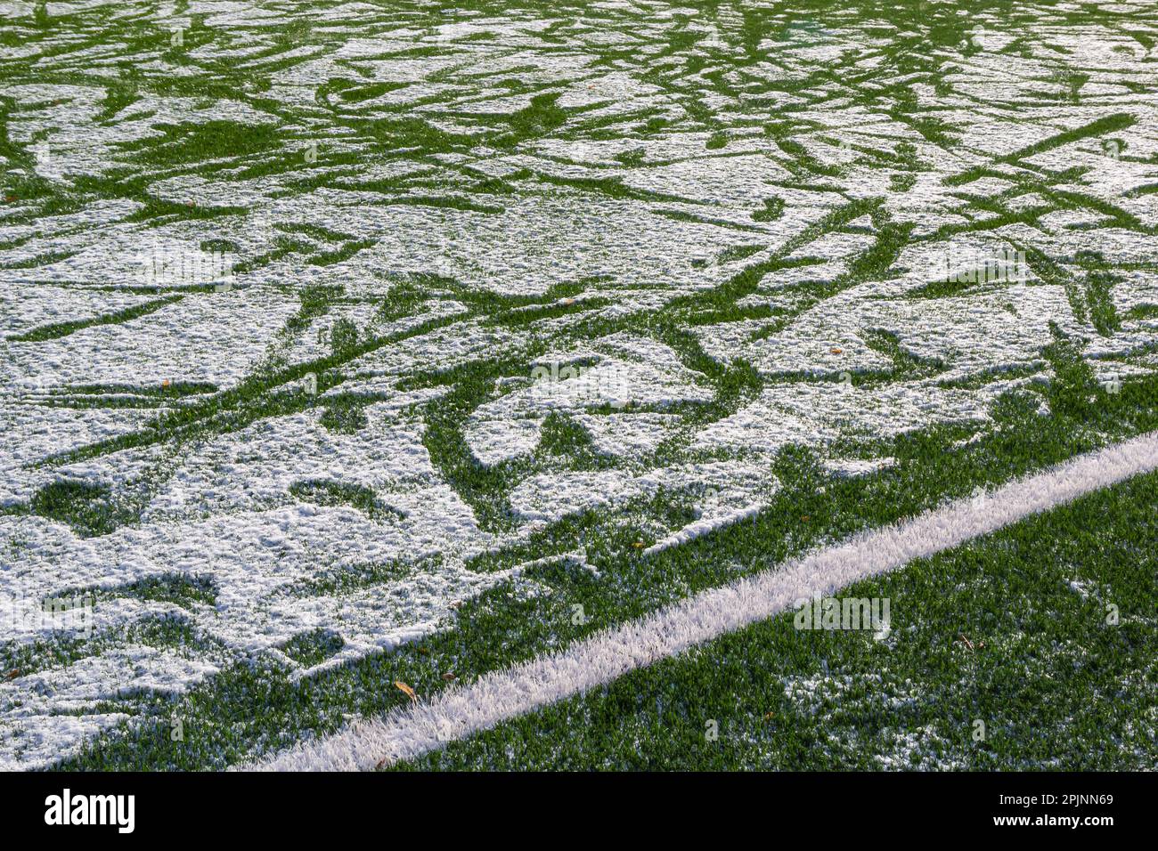 The football field with artificial green grass is covered with a light ...