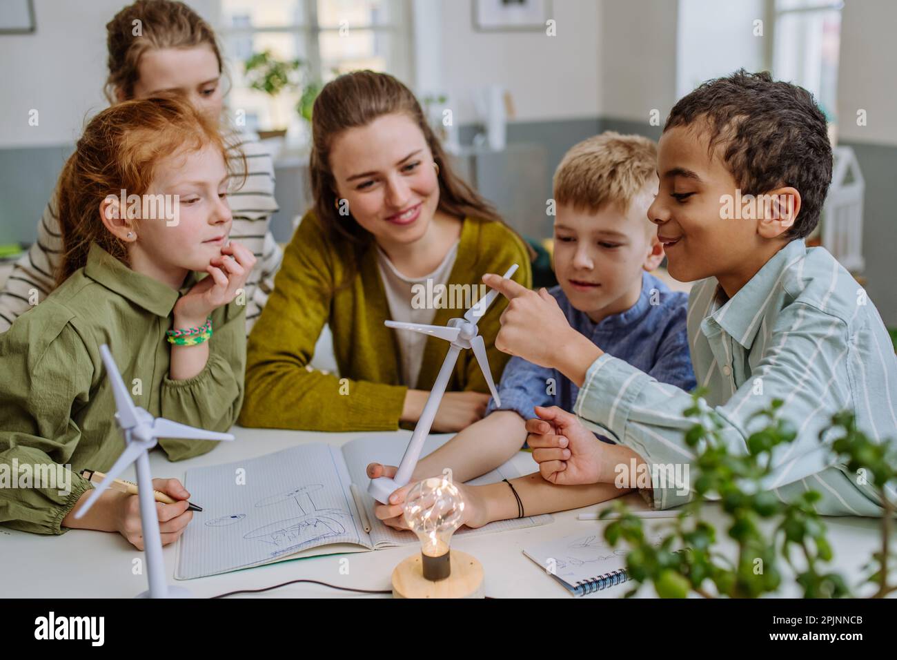 Young Teacher With Model Of Wind Turbine Learning Pupils About Wind
