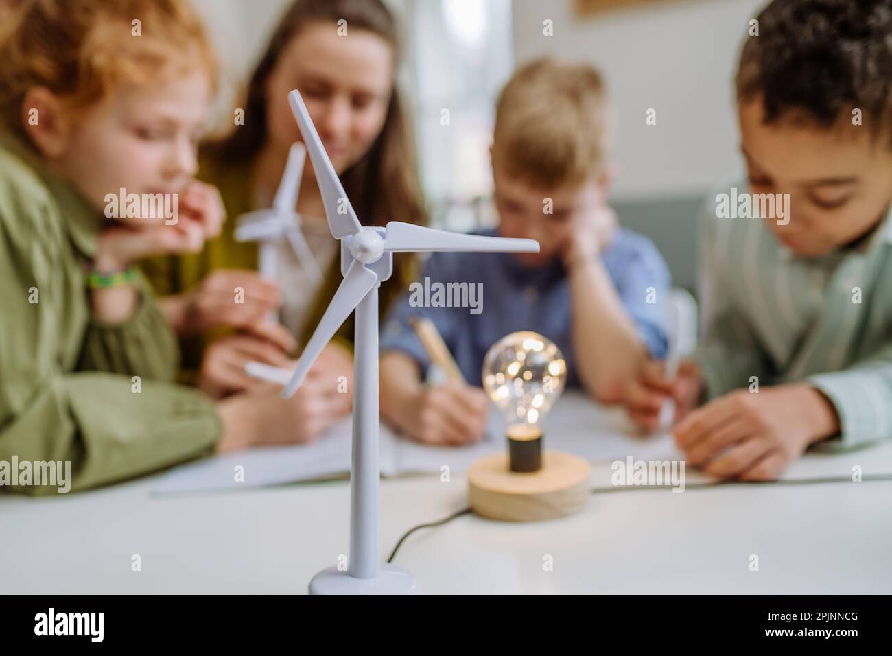 Young teacher with model of wind turbine learning pupils about wind ...