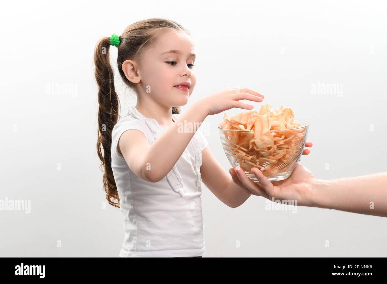 Little girl is given a big bowl of chips snacks with lard, white ...