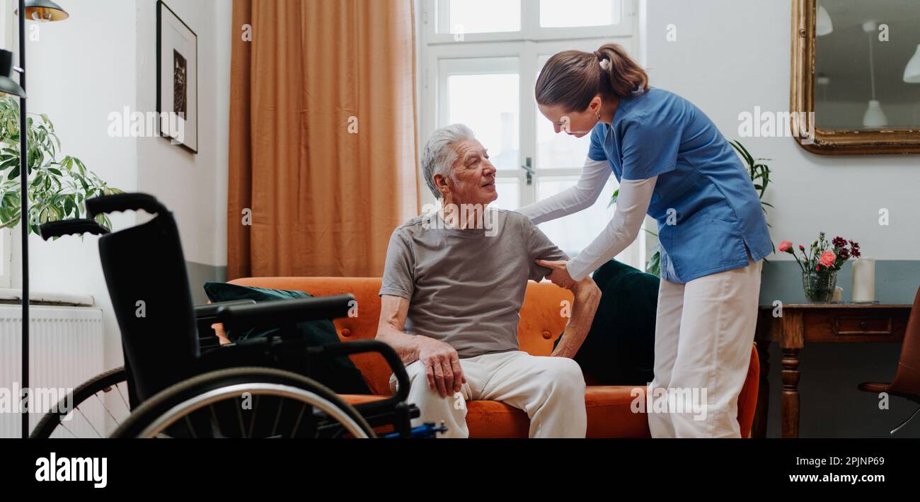 Young nurse helping senior man to stand up Stock Photo - Alamy