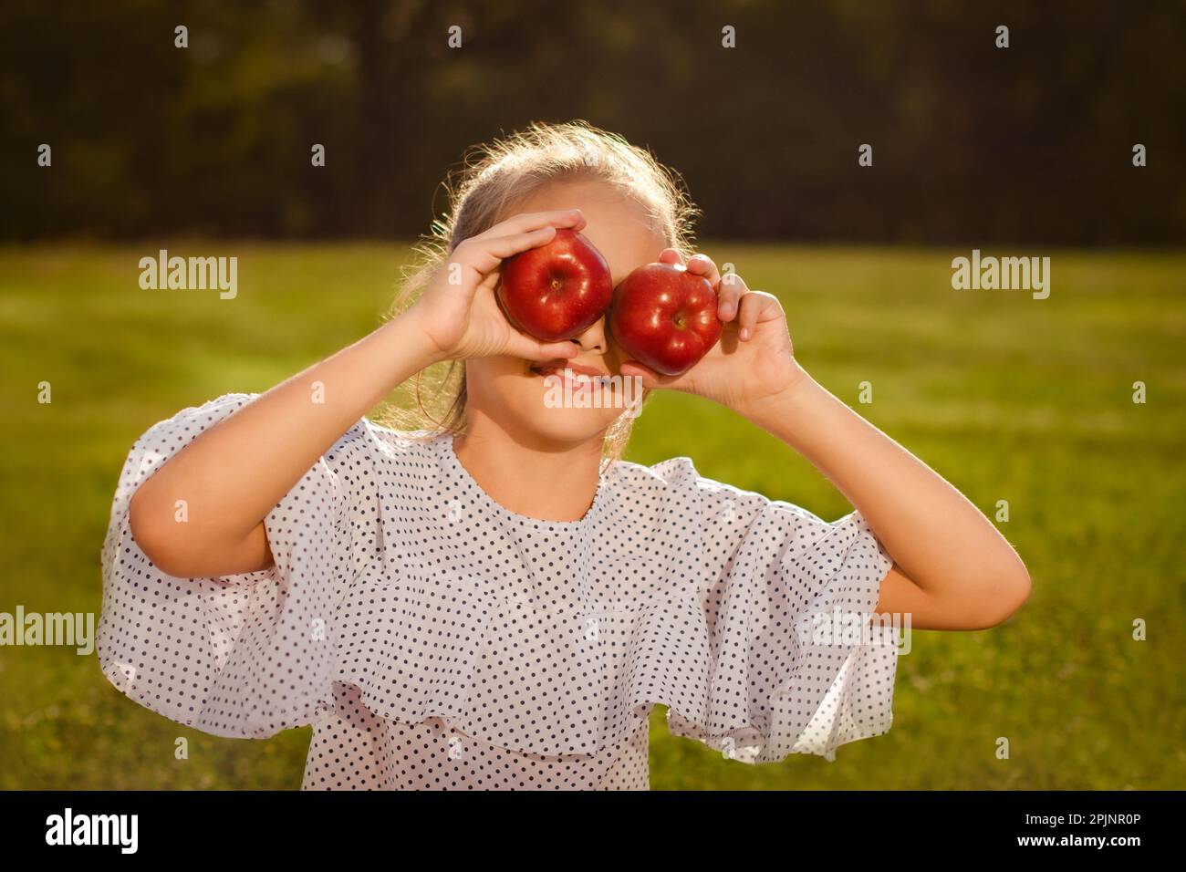 funny child girl play with apples and rest in green park in summer ...