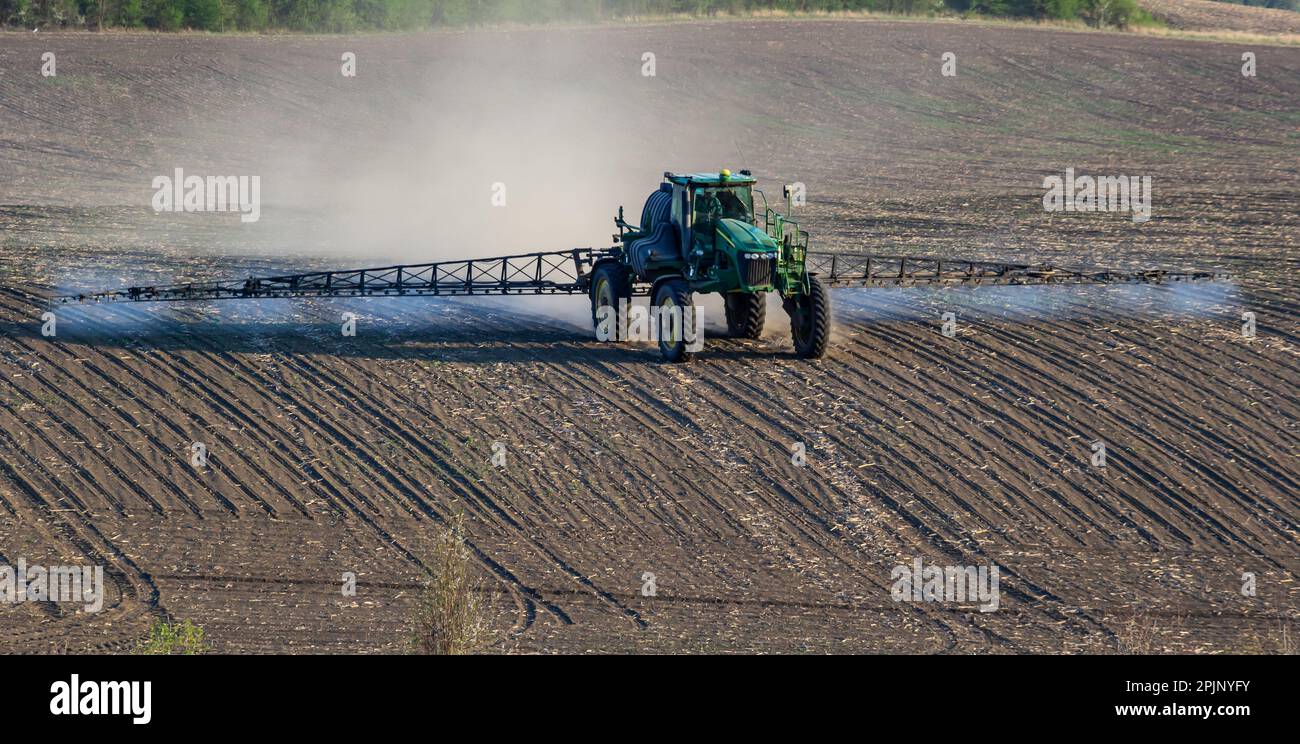 Tractor spraying pesticides on vegetable field with sprayer at spring ...