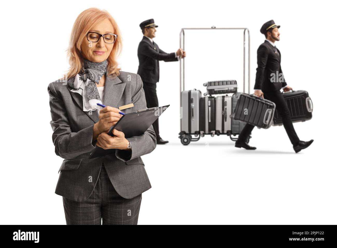 Bellboys carrying suitcases with a luggage cart and female hotel ...