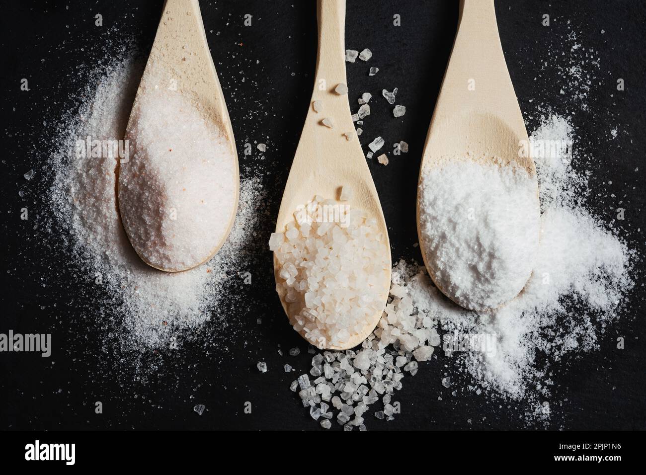 Three types of salt on a black background. Sea, himalayan and table ...