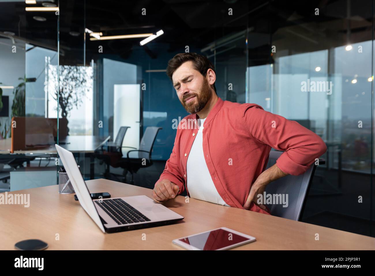 Back pain at the workplace. A young male programmer, freelancer sits in ...