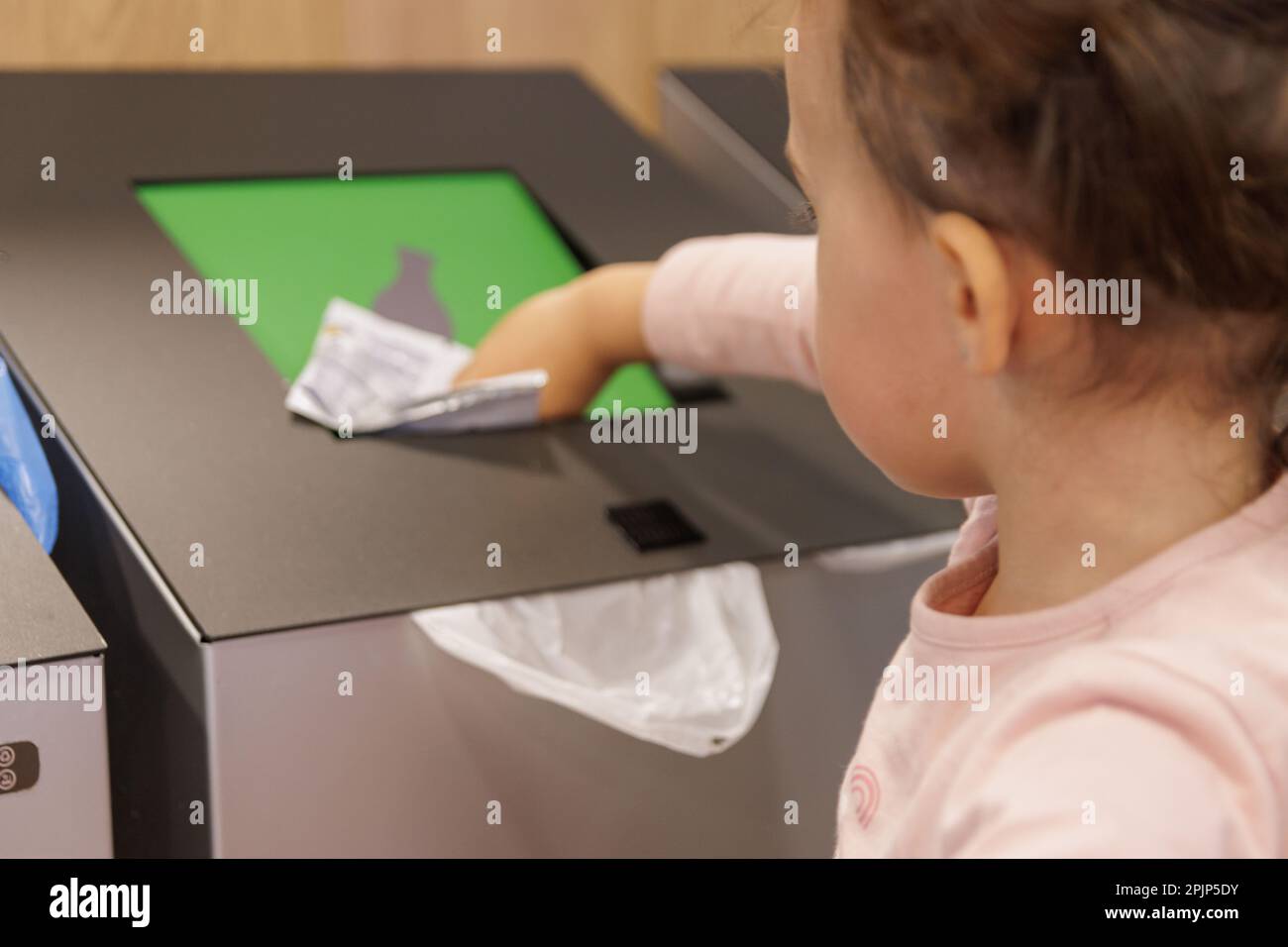 Little girl throwing container into recycle bin Stock Photo - Alamy