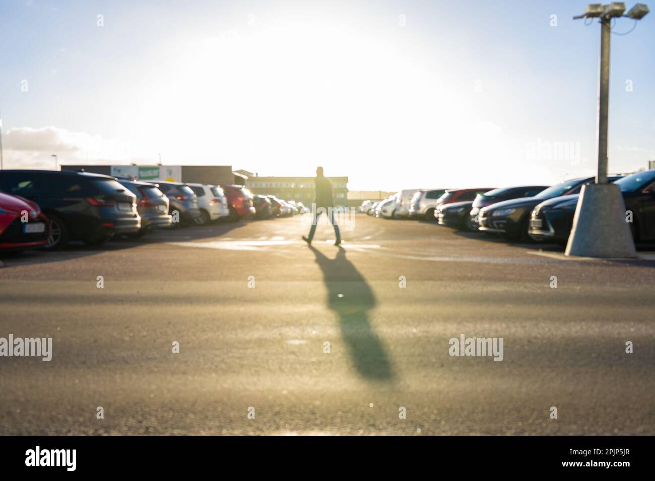 Out of focus image of a person walking across a parking lot Stock Photo ...