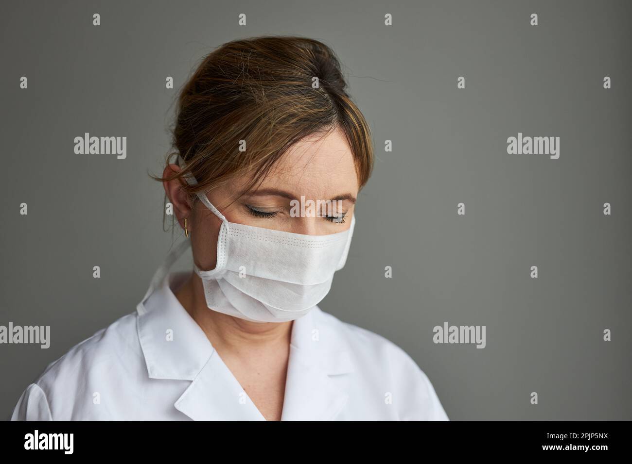Doctor with face covered with mask. Portrait of young woman wearing the ...