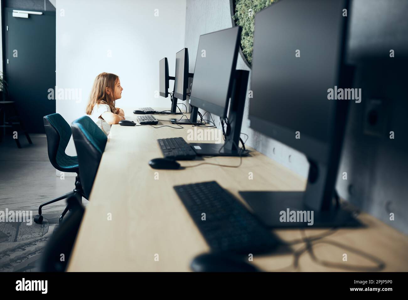 Engaged schoolgirl learning to use technology in classroom at primary ...