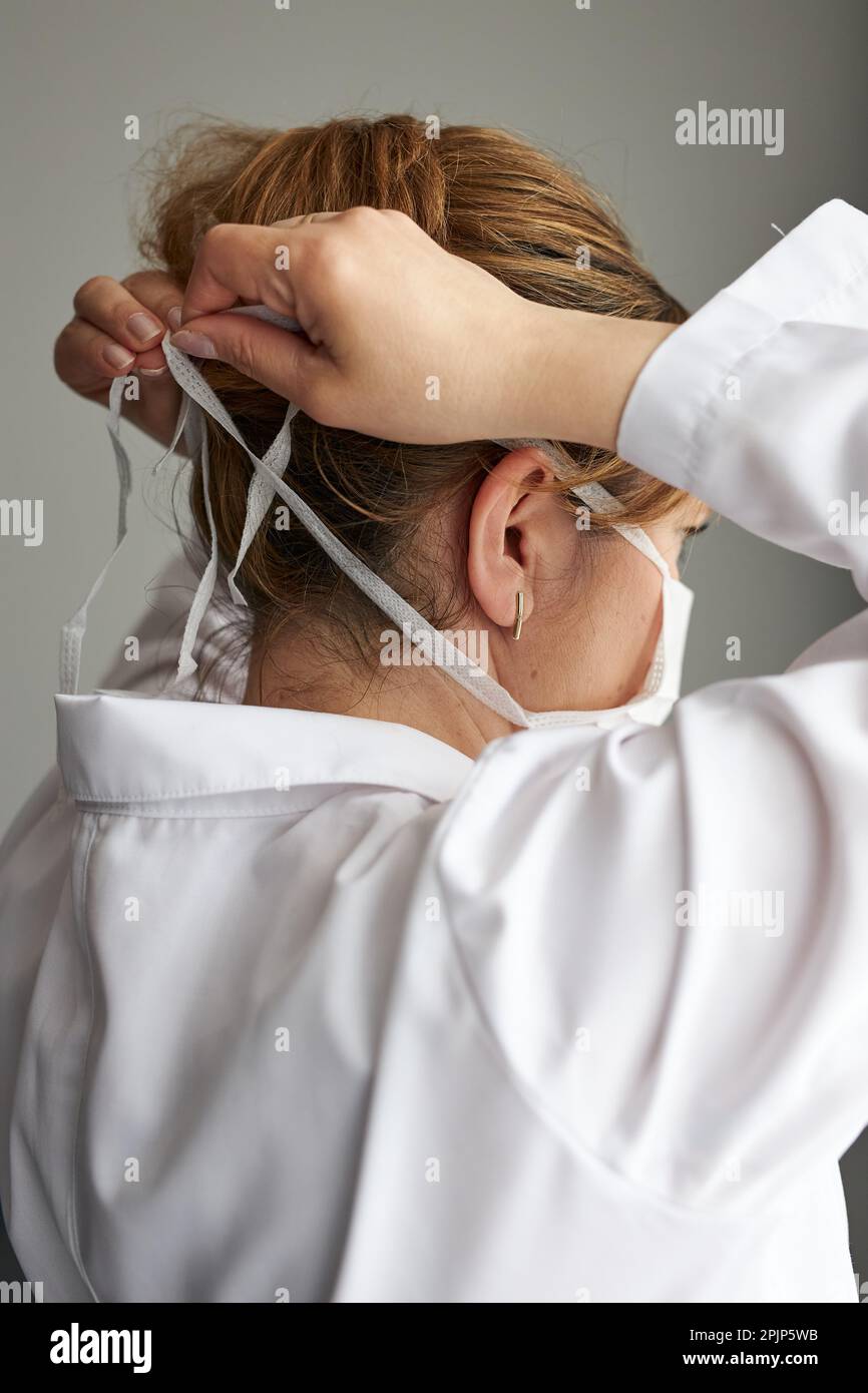 Doctor covering her face with mask. Portrait of young woman wearing the ...